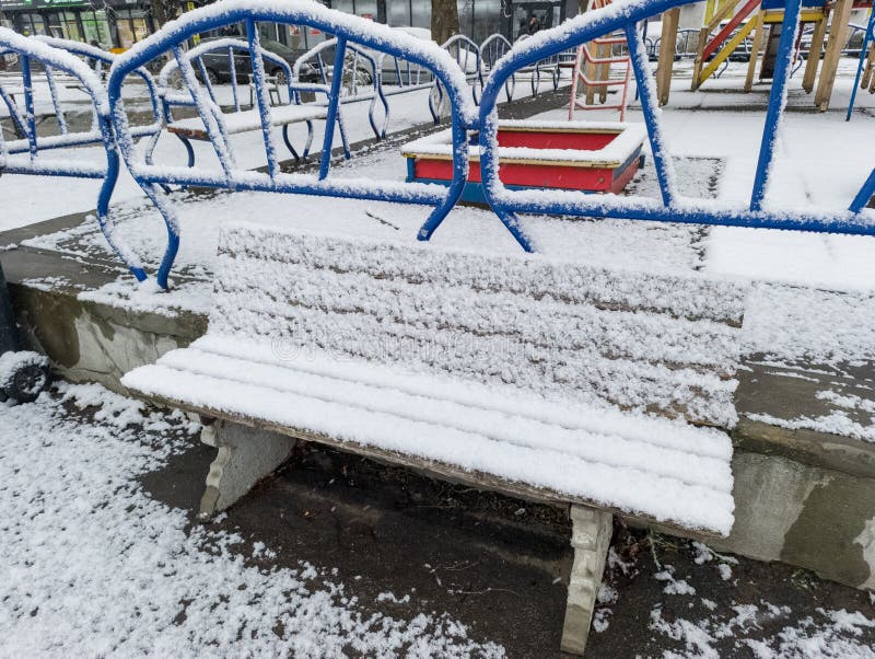 A Park Bench Covered in Snow Next To a Playground Stock Image - Image ...