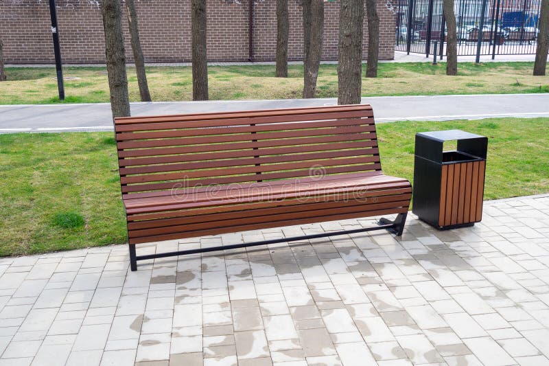 Park Seating Area Features a Slatted Wooden Bench and a Matching Trash ...