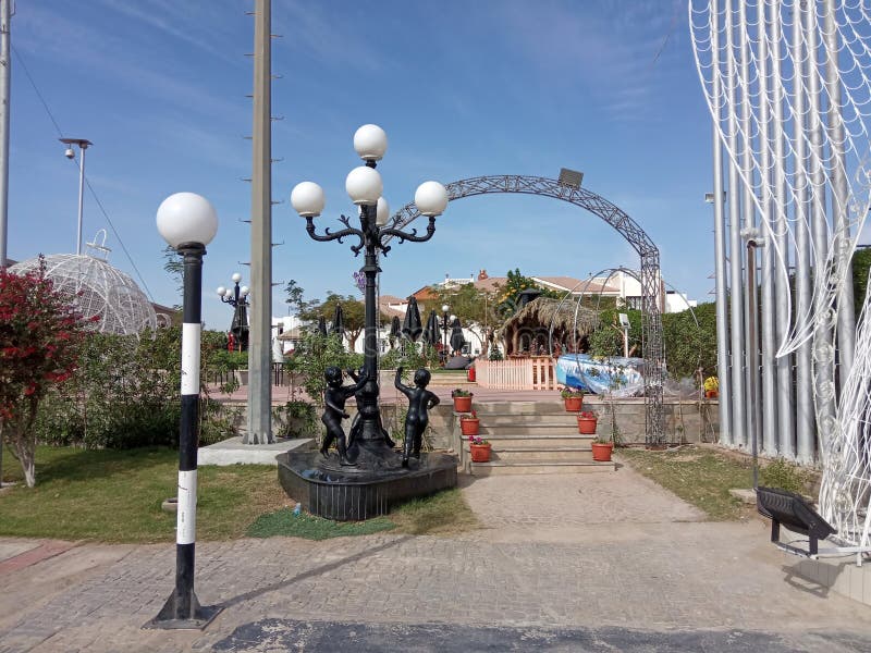 A Park with a Statue of Children and an Ornate Lamp Post Under a Clear ...