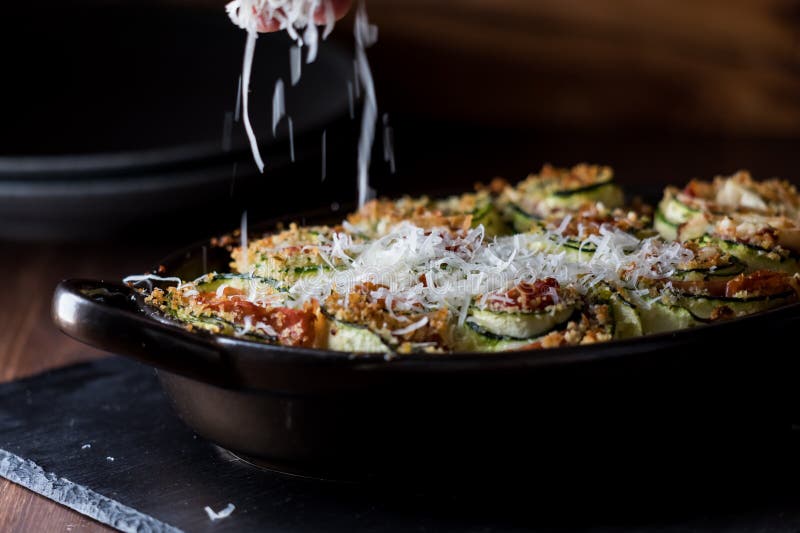 Parmesan Cheese in Soft Focus Being Sprinkled on Top a Dish of Zucchini ...