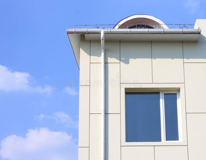 Part of a Building Wall with Window and Gutter Against the Blue Cloudy ...