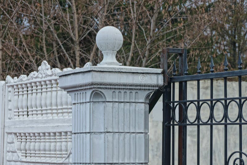 Part of a White Concrete Column with a Stone Ball in a Black Iron Fence ...