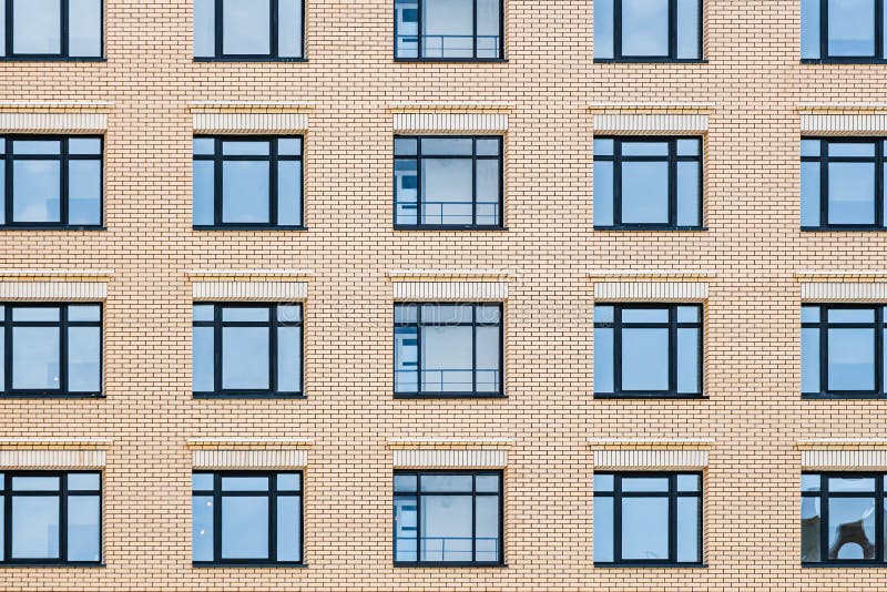 A Part of a Yellow Brick Wall with a Group of Blue Windows with ...