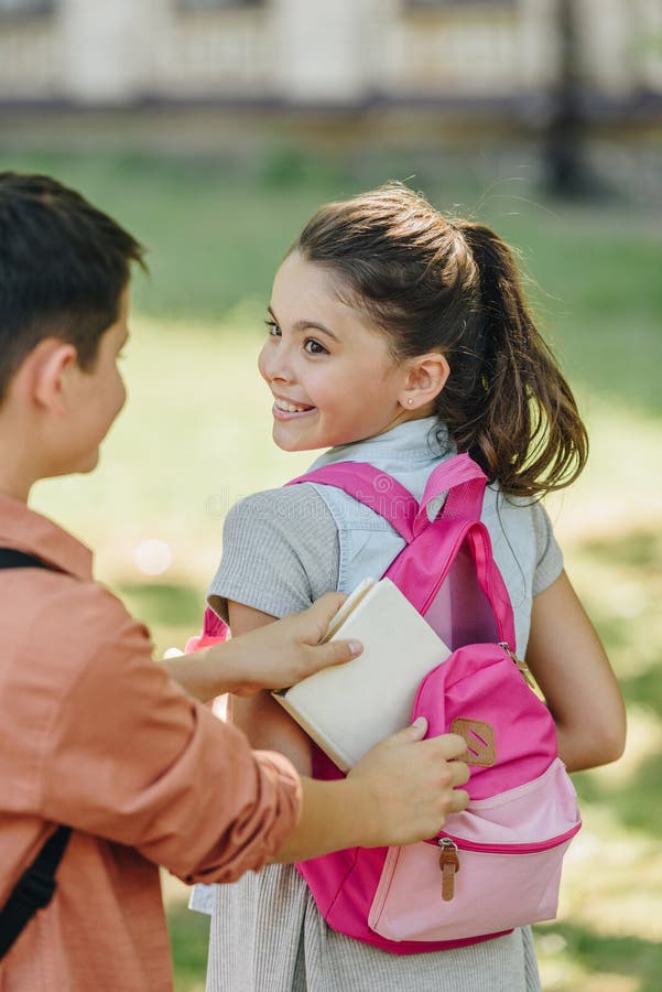View of Schoolboy Packing Book in Backpack of Cheerful Schoolgirl Stock ...