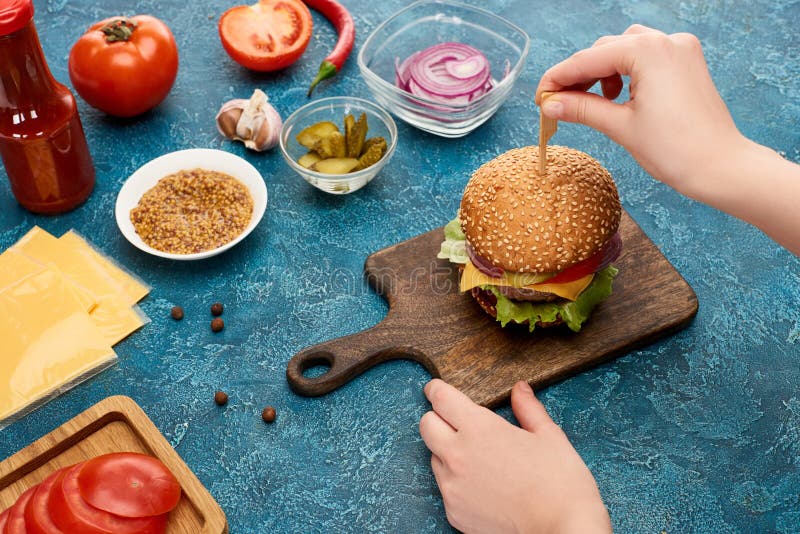 Partial View of Woman Cooking Delicious Burger on Blue Textured Surface ... Partial View of Woman Cooking Delicious Burger on Blue Textured Surface ...