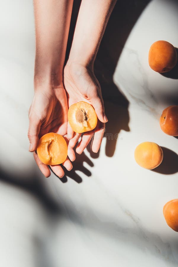 Partial View of Woman Holding Pieces of Ripe Apricots in Hands on Light ... Partial View of Woman Holding Pieces of Ripe Apricots in Hands on Light ...