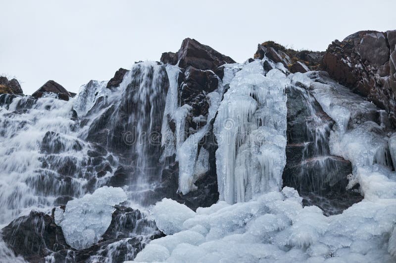 Partially Frozen Waterfall Flows Amidst Ice Formations on a Rugged ...