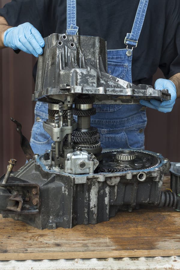The Passenger Car Gearbox is on the Table. the Mechanic`s Hands Remove ...