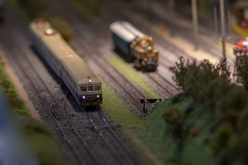A Passenger Train with Its Headlights on Rides on Rails, a Toy Train ...