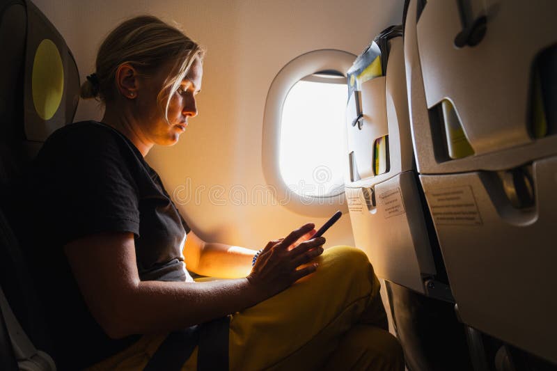 Passenger Woman Is Flying In Plane Girl Using Phone Sitting By