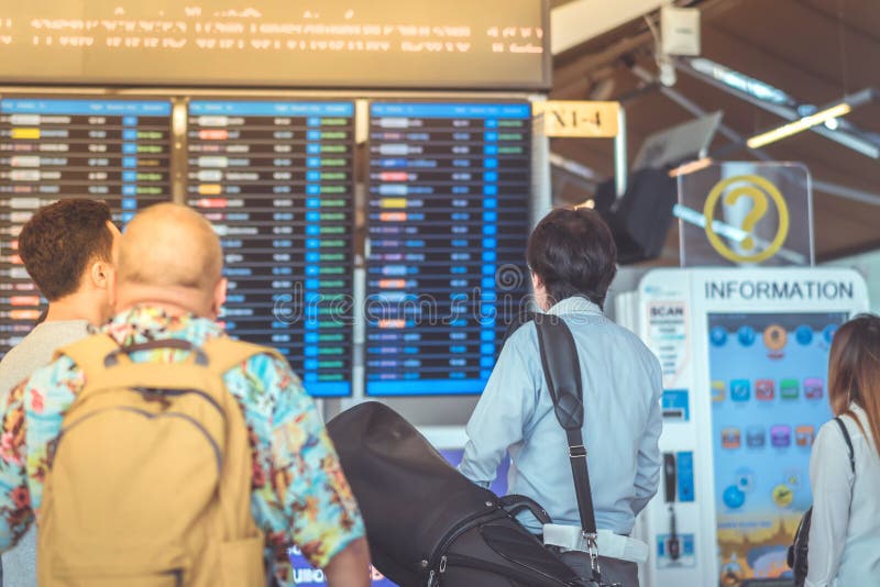 Passengers Looking at the Flight Information Board and Checking Their ...