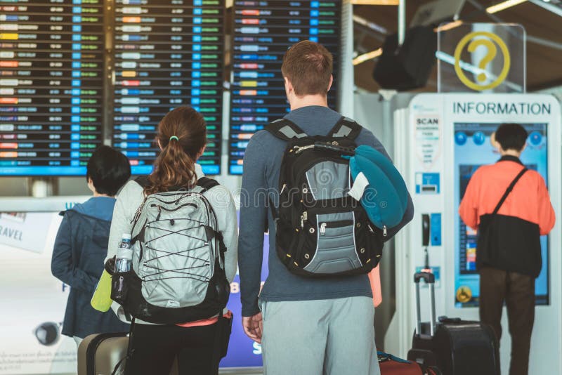 Passengers Looking at the Flight Information Board and Checking Their ...