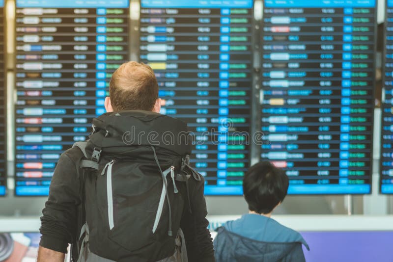 Passengers Looking at the Flight Information Board and Checking Their ...