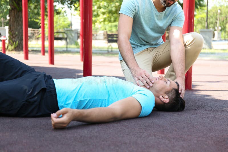 Passerby Giving First Aid To Unconscious Man Outdoors Stock Photo ...