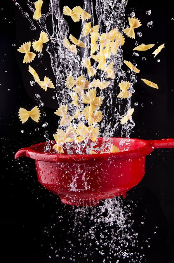 Pasta Falls Into The Red Colander With Splashes Of Water Stock Photo ...