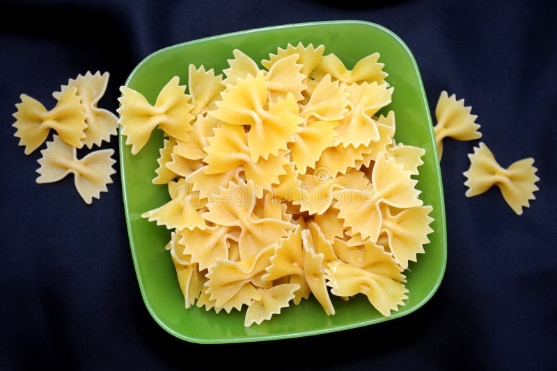 Pasta in the Shape of a Bow in a Green Bowl on a Blue Background Stock ...