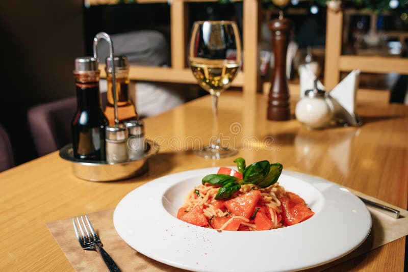 Pasta Tagliatelle with Tomatoes on a White Plate on a Table in a ...