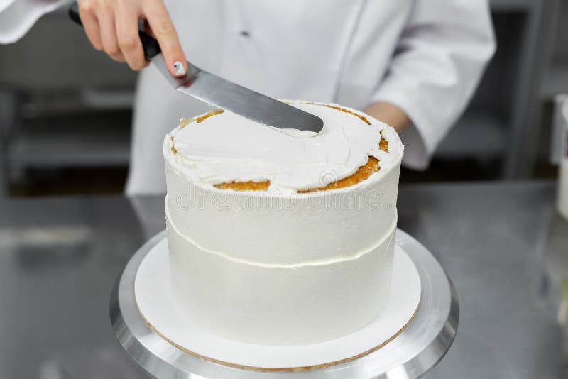 The Pastry Chef Levels the Cake with Cream. Stock Photo - Image of ...