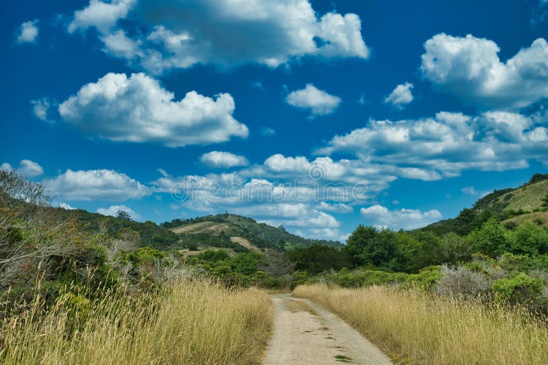 Path through Valley Leading To Mountains Under the Blue Sky Stock Image ...