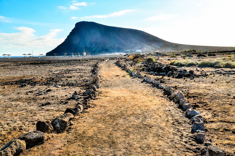 A Path Winds through a Desert with a Large Mountain in the Background ...