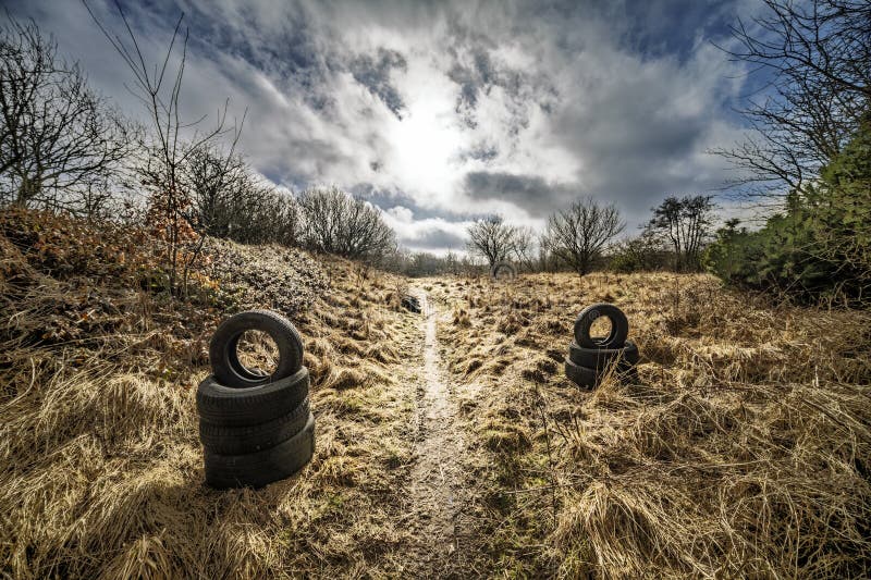 Pathway through Rural Landscape with Discarded Tires Under Cloudy Sky ...