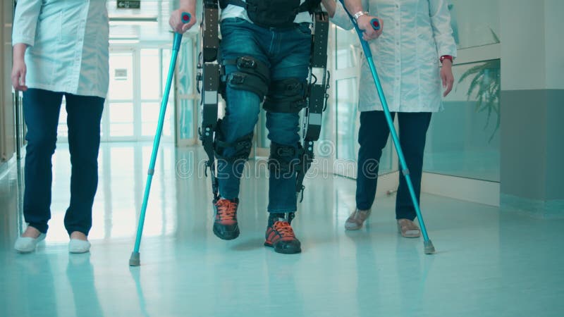 A Patient in the Exoskeleton is Walking with Nurses Help Stock Video ...