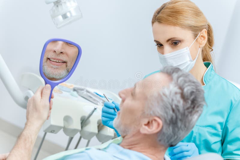 Patient Looking at Mirror while Professional Dentist Checking Teeth ...