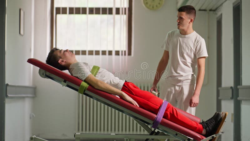 Patient Lying on a Tilting Therapy Table Secured with Straps, while a ...