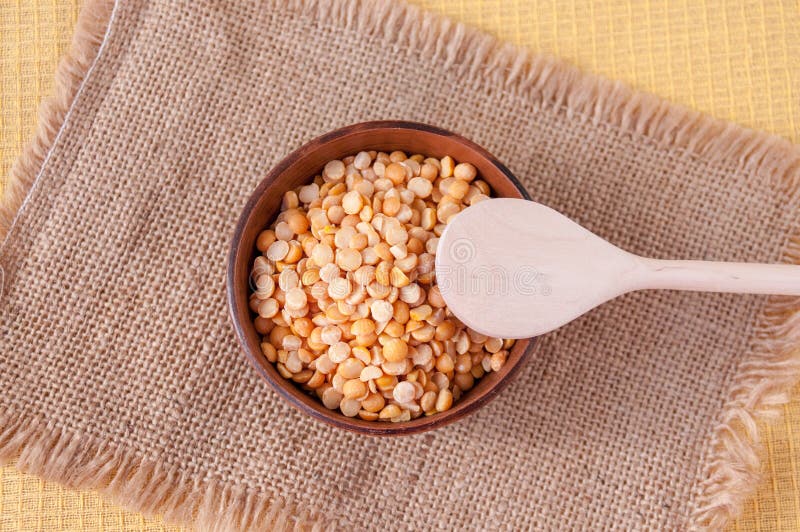 Pea Groats in a Clay Cup and a Wooden Spoon on a Burlap Table, Top View ...