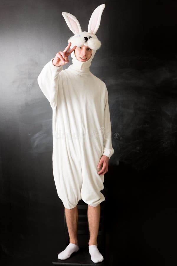 Man in a White Full Body Rabbit Costume Holding a Carrot To His Head ...