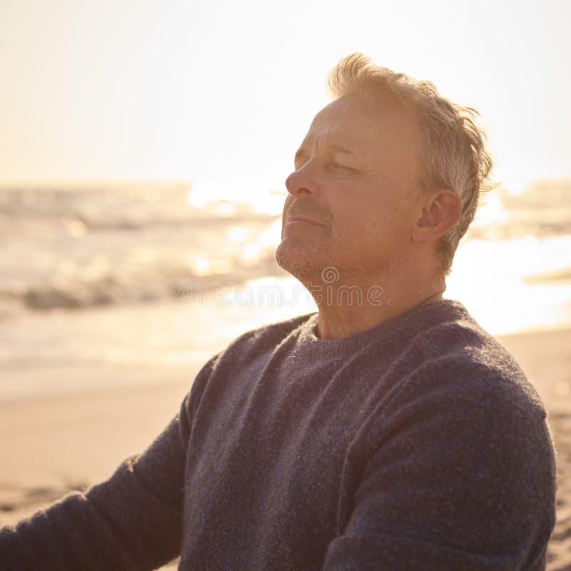 Peaceful Senior Man Relaxing Sitting On Beach Shoreline With Closed