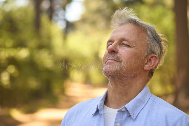 Peaceful Senior Man Relaxing Standing Amongst Nature In Forest