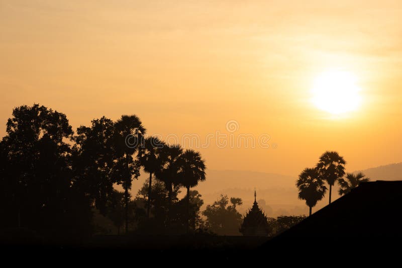 A Peaceful Sunrise with Warm Colors, Silhouetted Trees, and a Temple in ...