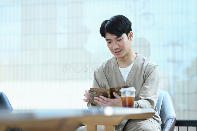 Peaceful Young Asian Man Reading a Book while Relaxing in the Cafe ...