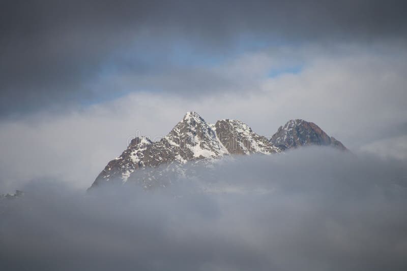 Peak of High Mountain Range through Clouds Stock Photo - Image of ...
