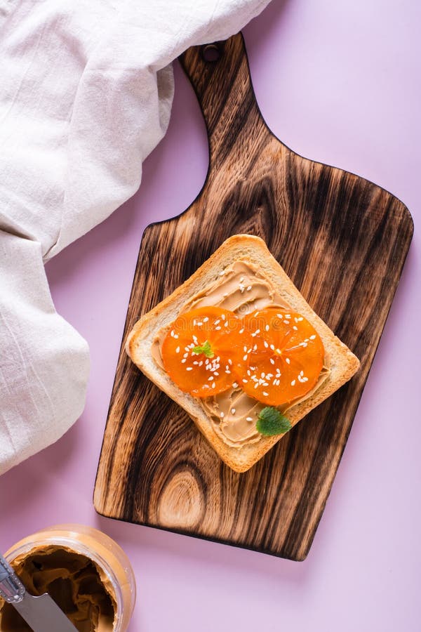 Peanut Butter Toast with Persimmon, Sesame and Mint on a Cutting Board ...