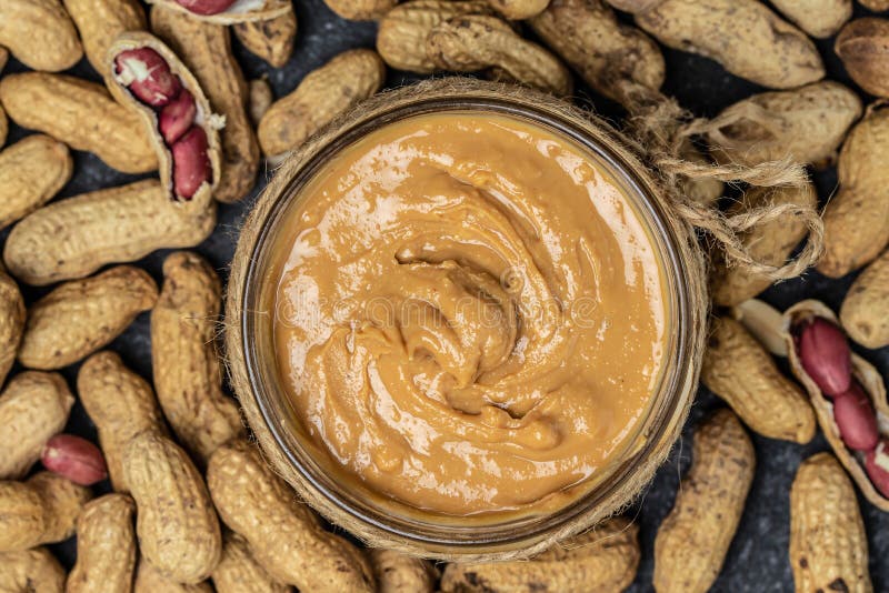 Peanut Paste in an Open Jar. Creamy Peanut Butter Peanuts Scattered ...