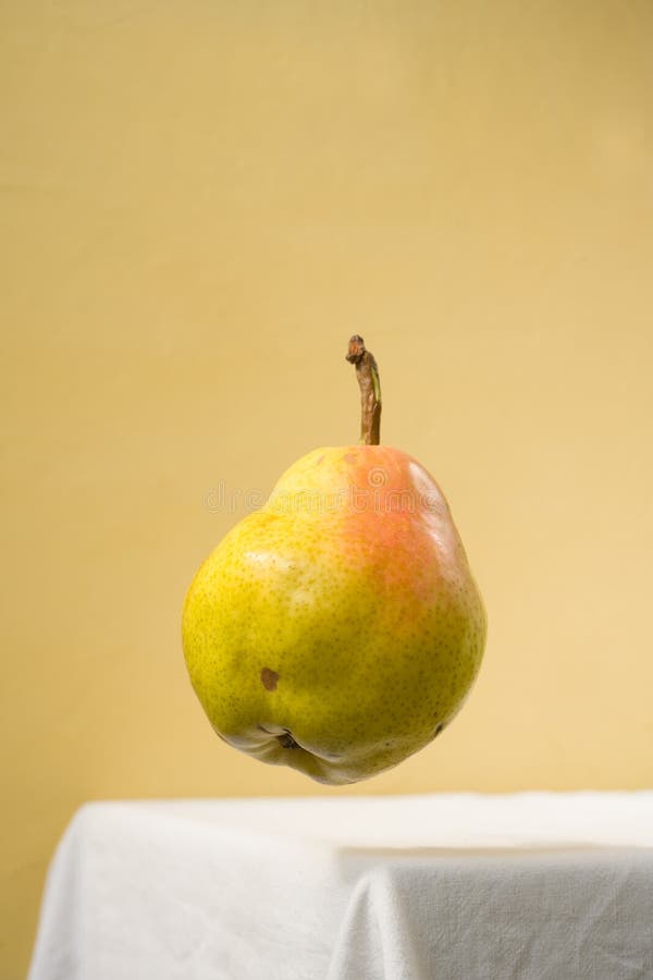 Pear Floating in the Air on a White Table and Yellow Background Stock ...