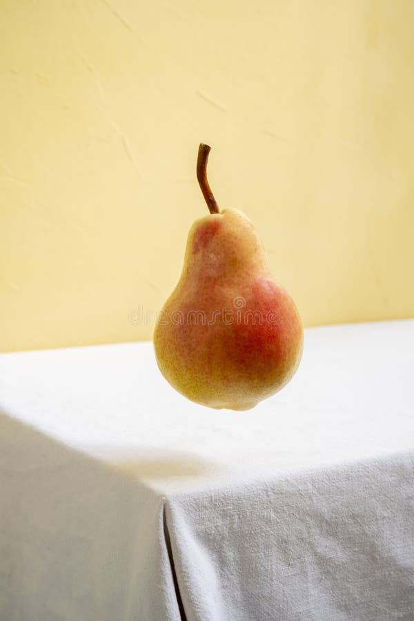 Pear Floating in the Air on a White Table and Yellow Background Stock ...