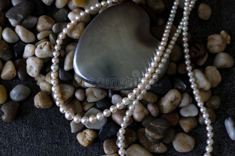 Pearl Necklace and Heart Shaped Metal Object Isolated on Stone Pattern ...