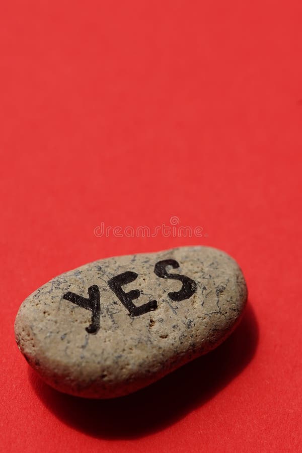 Pebble Stone with Black Text Yes on Red Table Stock Image - Image of ...