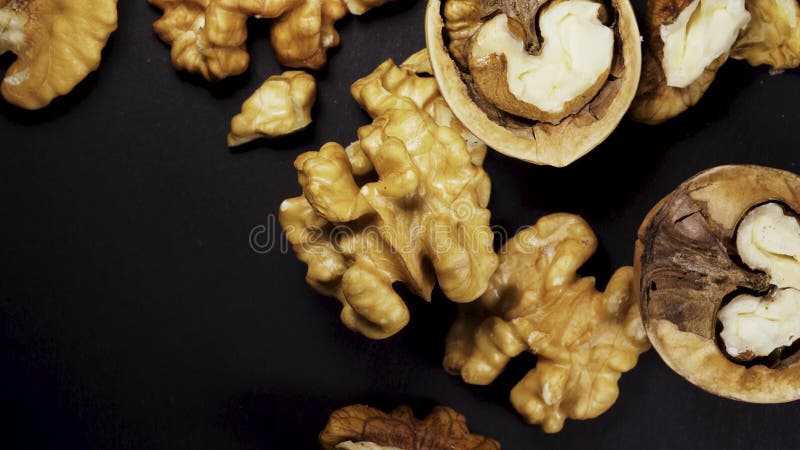A Peeled Walnut Rotates on a Black Background. the Nuts are Falling ...