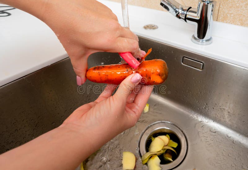 Peeling a Carrot Over the Kitchen Sink with Running Water and Waste ...