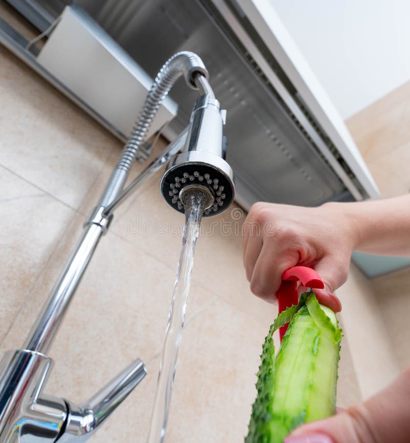 Peeling a Fresh Cucumber Under Running Water Using a Red-handled Knife ...