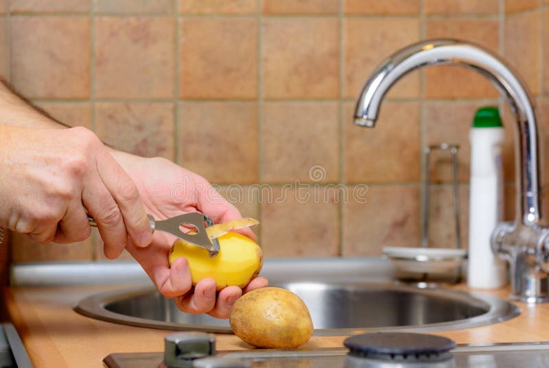 Peeling a Potato with Peeler in a Kitchen Stock Image - Image of ...