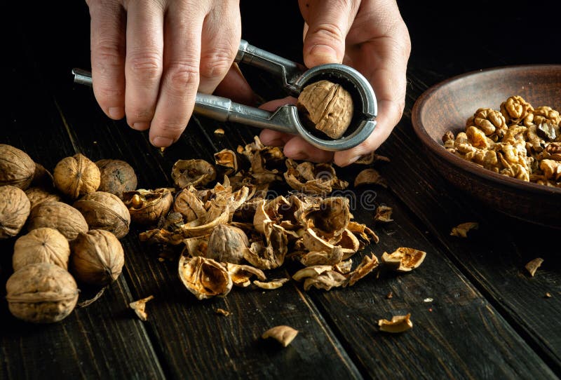 Peeling Walnuts with a Nutcracker in Hands of a Cook. Peeled Walnuts in ...