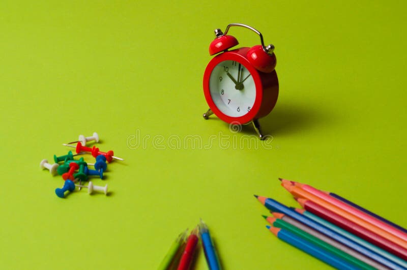 Pencils, Pens, Push Pins and Clock on Green Designer Paper Stock Photo ...
