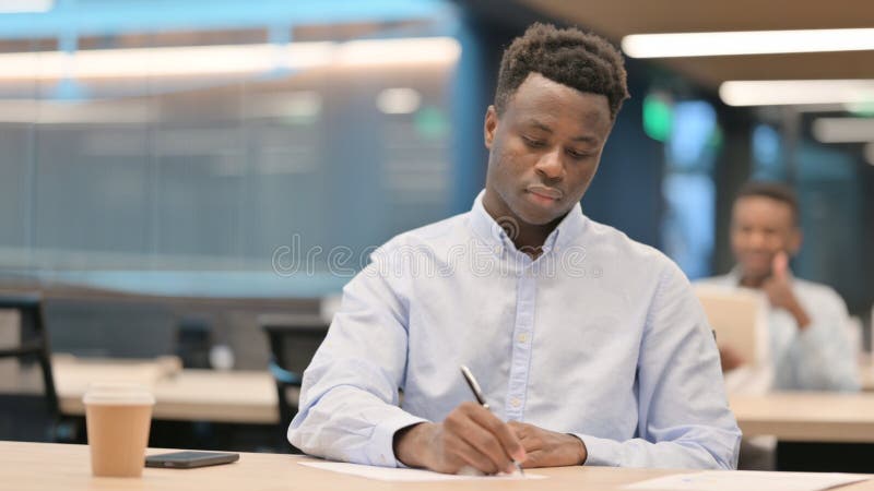 Pensive African Businessman Writing on Paper, Thinking Stock Image ...