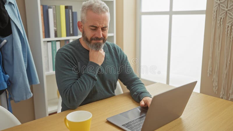 A Pensive, Bearded, Middle-aged Man with Grey Hair Using a Laptop in a ...