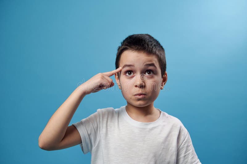 Boy Pointing with Forefinger To Temple while Standing on Blue ...